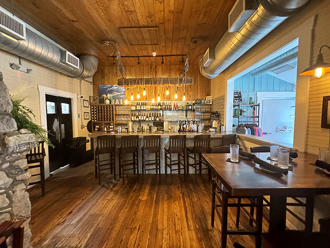 The bar area combines rustic wooden warmth with industrial touches that say, "We're serious about both atmosphere and libations." Edison bulbs create that perfect golden glow for decision-making.