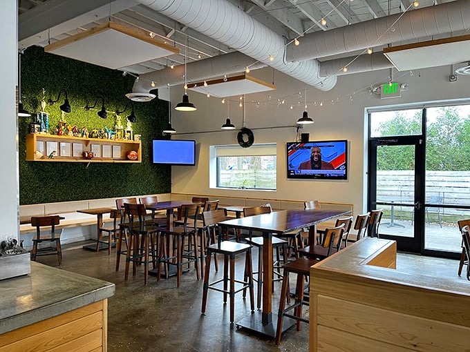 Industrial-chic meets comfort in this modern dining space, where the green wall brings nature indoors and the exposed ductwork keeps things refreshingly unpretentious.