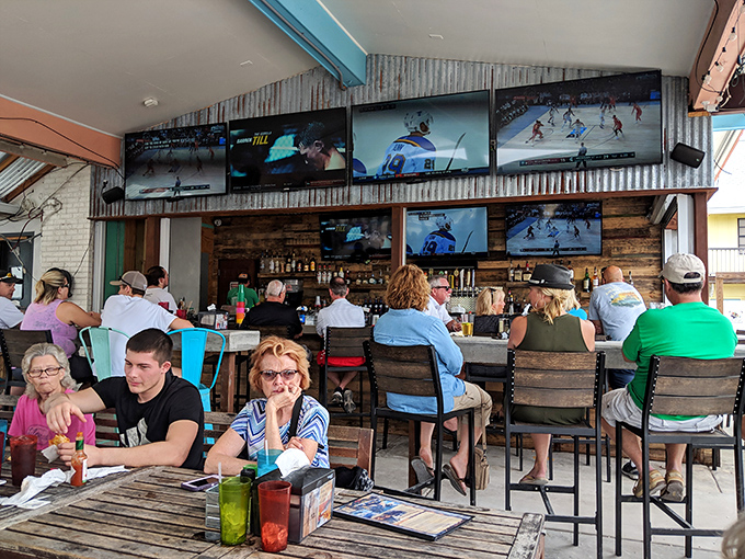The rustic bar area combines weathered wood, corrugated metal, and multiple TVs—a perfect spot for catching the game while catching up with friends.