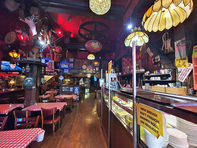 Step inside and time stops – flower-shaped lamps hang from a ceiling cluttered with memorabilia, while checkered tablecloths promise honest food ahead.