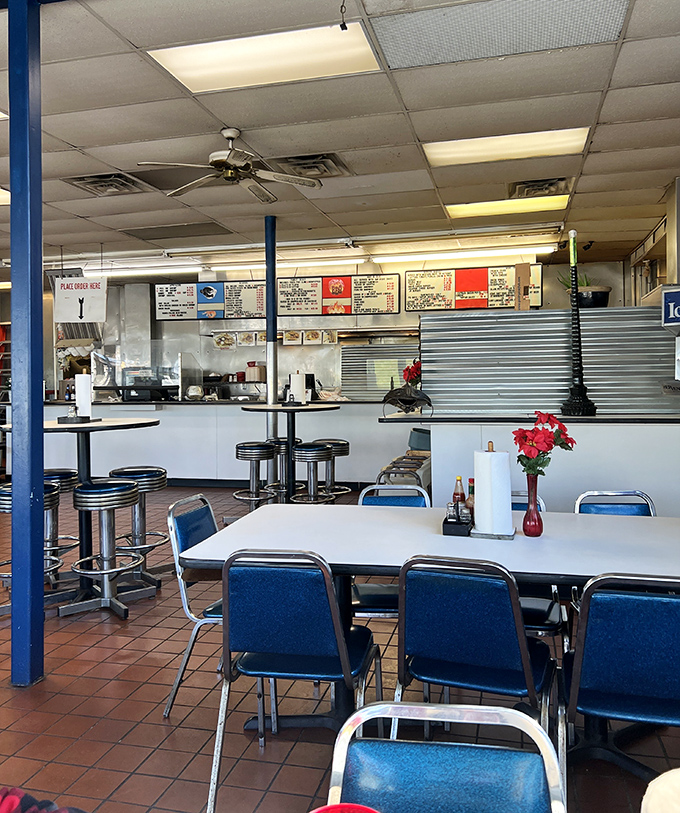 No-frills dining at its finest—blue chairs, ceiling fans, and a menu board that promises more flavor than flash.