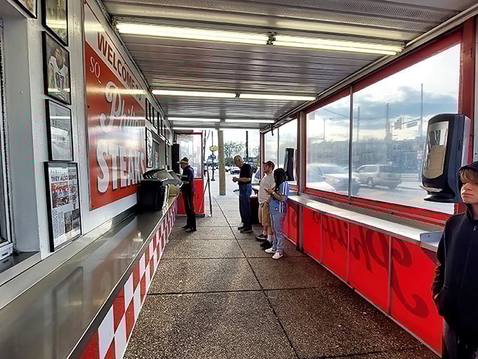 The line forms with purpose—locals and visitors united in pursuit of cheesesteak perfection under the no-frills covered walkway.