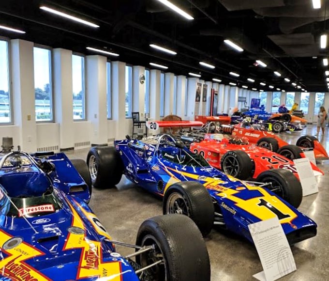A rainbow of racing royalty awaits inside, where these magnificent machines—once thundering around the track at 200+ mph—now rest in dignified retirement.