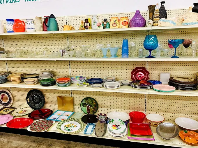 A rainbow of vintage glassware and dishes stands ready for adoption, each piece silently whispering stories of dinner parties past.