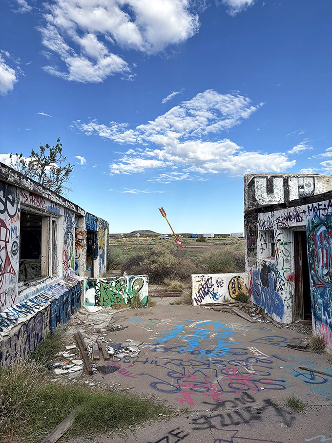 Nature's art gallery meets human creativity where crumbling walls frame the distant arrows, a perfect metaphor for Route 66's enduring legacy.