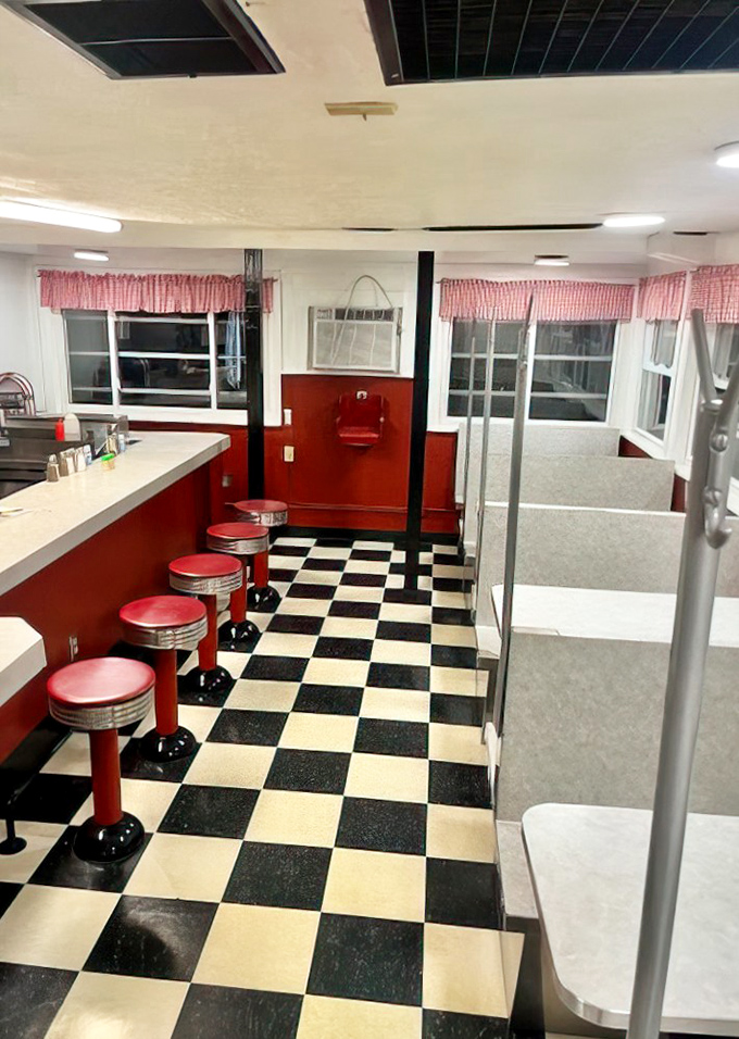 The classic black-and-white checkered floor and cherry-red counter stools aren't retro by design—they're authentic relics from an era when diners were America's living rooms.