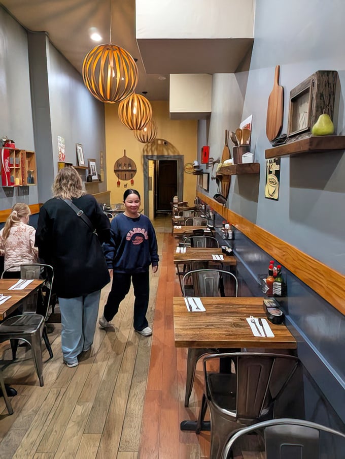 Narrow but mighty, the interior stretches like a railroad apartment where every inch is dedicated to the art of perfect breakfast. Those pendant lights cast a warm glow over morning conversations. 