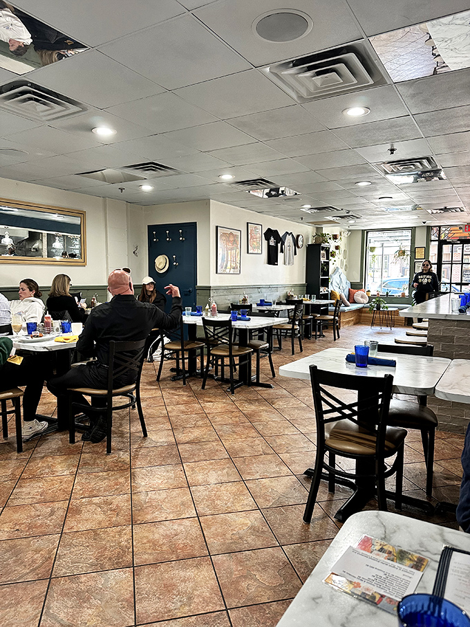 Inside, blue glasses pop against wooden tables while morning light streams through windows, creating that rare atmosphere where everyone looks like they actually slept well. 