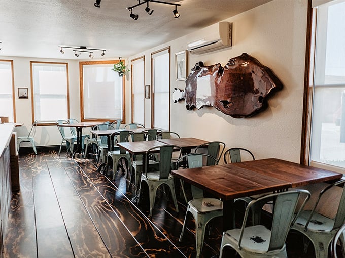 Simple, rustic elegance defines the interior where wooden tables and mint-green chairs create the perfect stage for the smoky drama about to unfold on your plate.