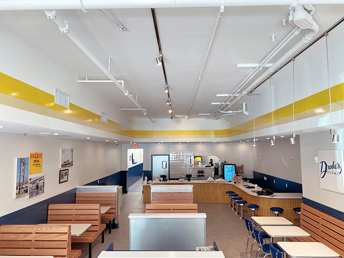 Clean lines, wooden benches, and that signature yellow stripe – Drake's interior is a masterclass in unpretentious dining where the food, not the decor, takes center stage.