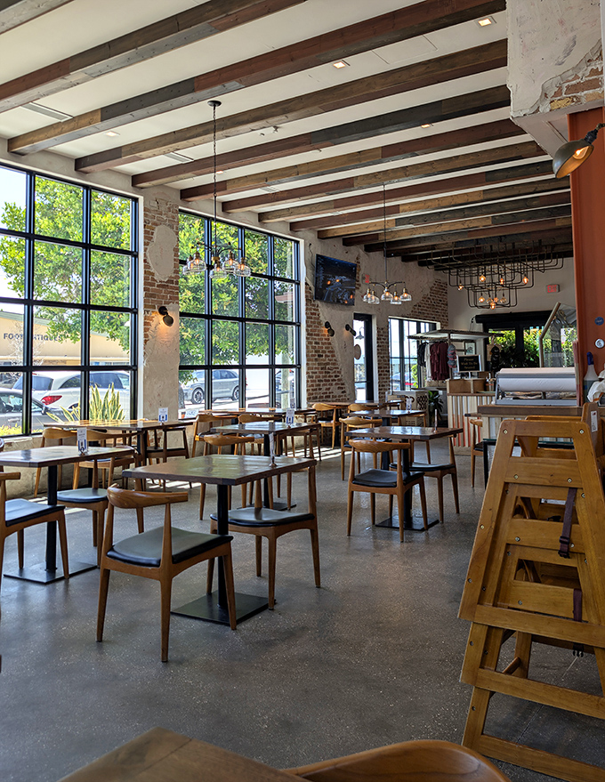 Sunlight streams through floor-to-ceiling windows, illuminating a dining room where industrial chic meets beachy comfort. Those wooden beams have witnessed countless BBQ epiphanies.