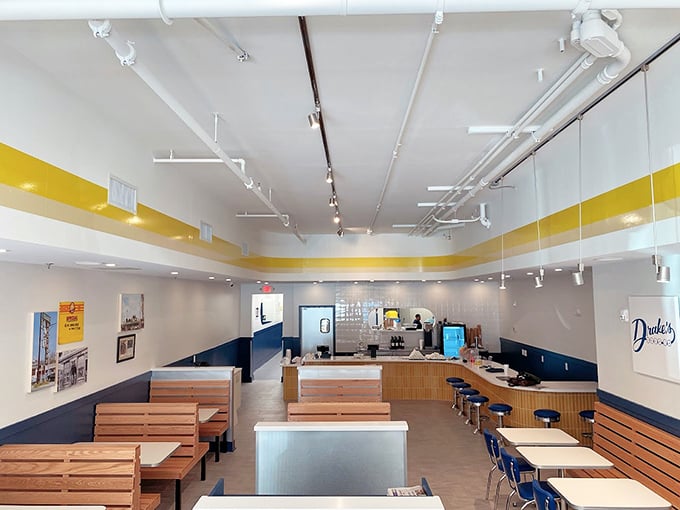 Clean lines, wooden benches, and that signature yellow stripe – Drake's interior is a masterclass in unpretentious dining where the food, not the decor, takes center stage.