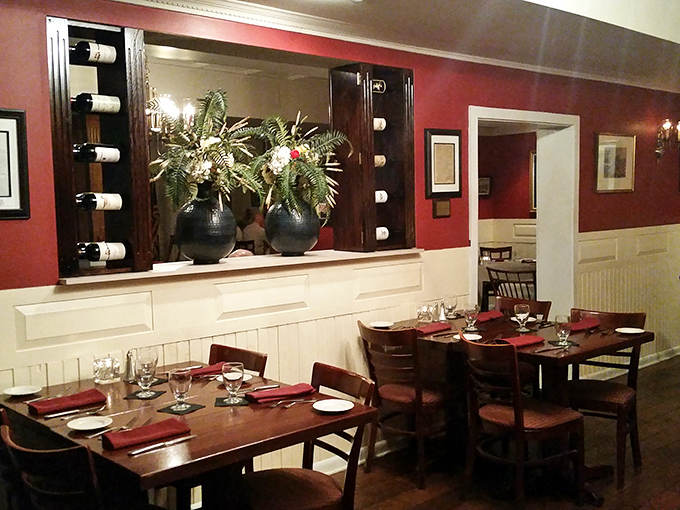 Rich burgundy walls and elegant wine displays create an atmosphere that whispers "special occasion" while the warm wood tones say "make yourself at home." 