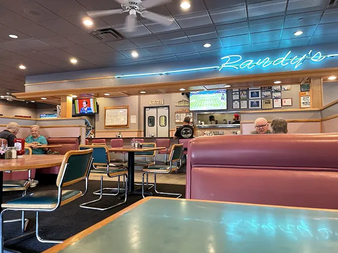 That neon blue sign beckons like an old friend, promising comfort food and conversations in those perfectly worn-in burgundy booths.