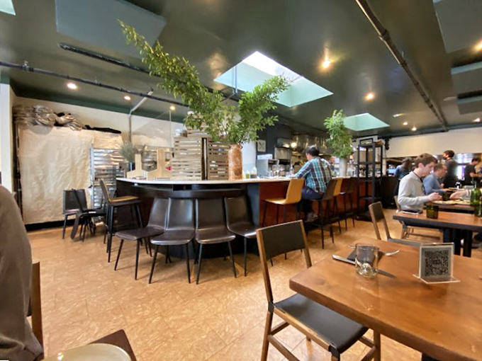 Skylights flood the dining room with natural light while hanging plants add life to a space where serious food comes with a side of relaxed ambiance.