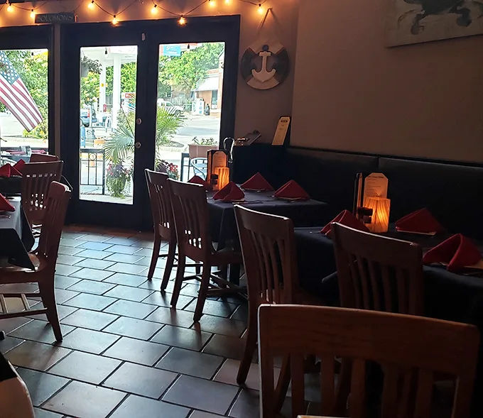 String lights cast a warm glow over wooden chairs and coral napkins—the perfect backdrop for seafood stories and second rounds.
