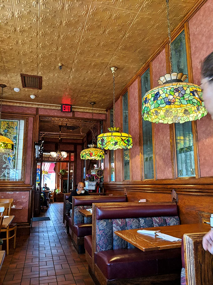 Step inside and time travels backward – Tiffany-style lamps cast a warm glow over wood-paneled walls and cozy booths where breakfast dreams come true.