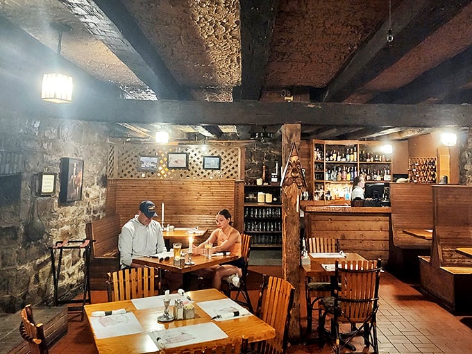 Low beams, stone walls, and wooden tables create a time-travel dining experience. This basement tavern space feels like stepping into Revolutionary-era America.
