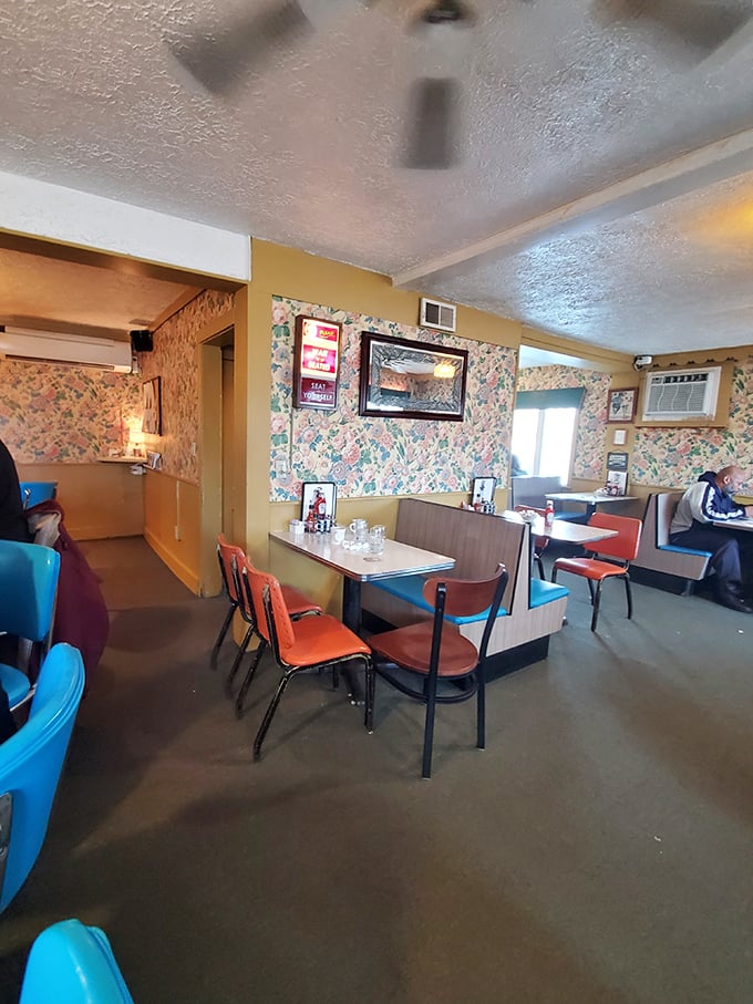 Classic diner aesthetics in full bloom – floral wallpaper, vinyl booths, and those unmistakable orange chairs that somehow feel like coming home.