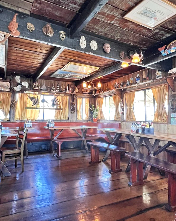 Masks watch over diners from wooden walls while yellow curtains frame marina views. This isn't Pinterest-perfect nautical—it's the authentic article.