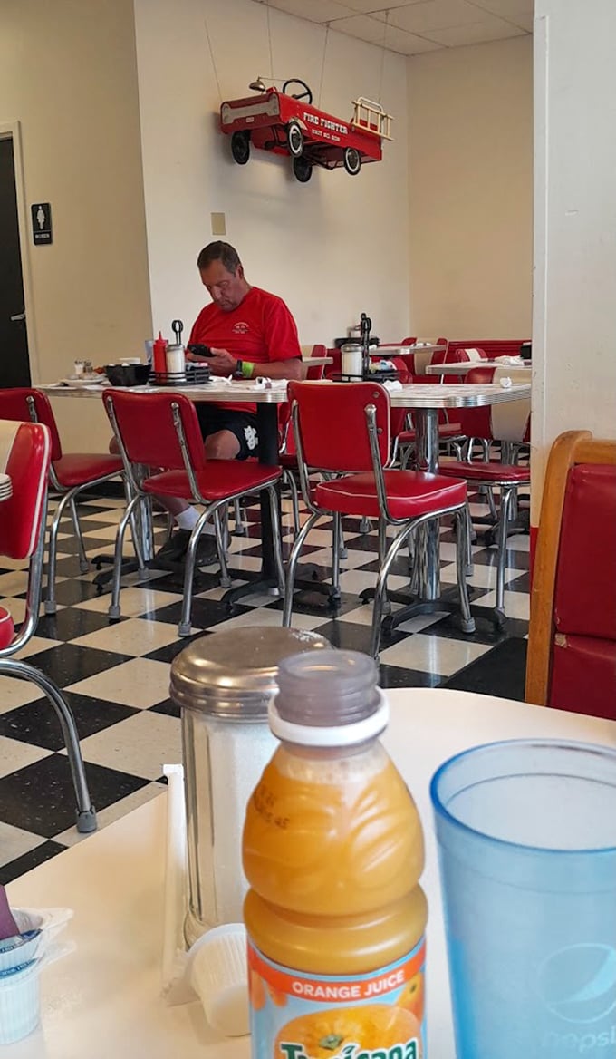 Where nostalgia meets nourishment: The quintessential American diner experience with checkerboard floors, red vinyl chairs, and a toy fire truck keeping watch overhead.