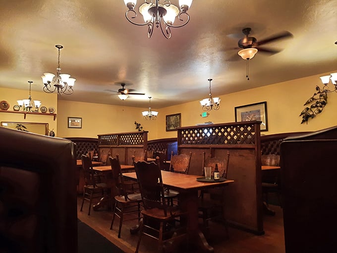 Wooden booths with lattice dividers create intimate dining nooks under warm chandeliers. The quintessential steakhouse ambiance that whispers, "You're about to eat really well."