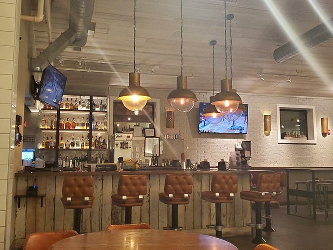 The bar area blends industrial chic with Texas warmth—leather stools practically begging you to settle in for a post-brisket bourbon.