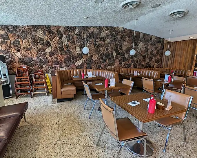 Mid-century magic meets breakfast bliss in these caramel-colored booths. The stone wall isn't just decor—it's practically a time machine to simpler days.