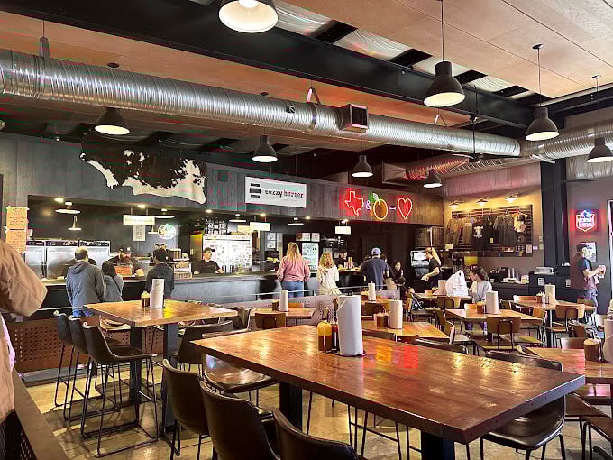 Industrial chic meets Texas warmth in ZZQ's dining room. The neon Lone Star State outline isn't just decoration—it's a promise.