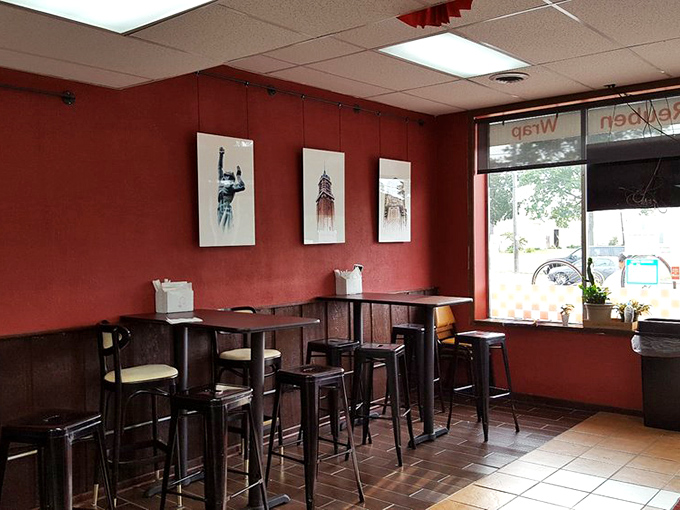 Red walls and simple seating create the perfect backdrop for sandwich artistry. No distractions here—just you and your imminent Reuben rendezvous.
