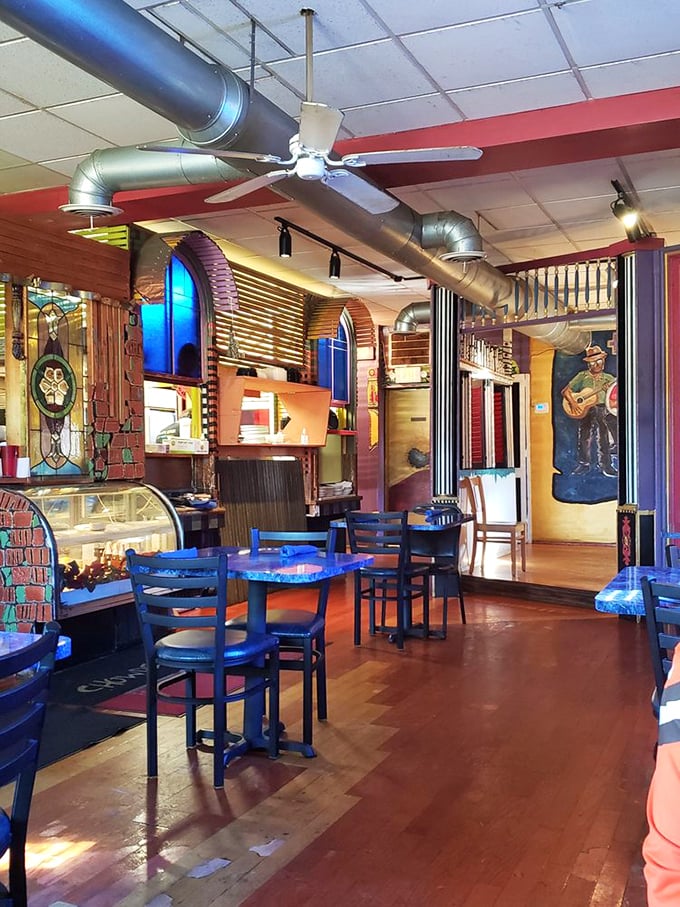 Stained glass windows cast kaleidoscope shadows across wooden floors while exposed ductwork plays industrial counterpoint to whimsical maritime decor.