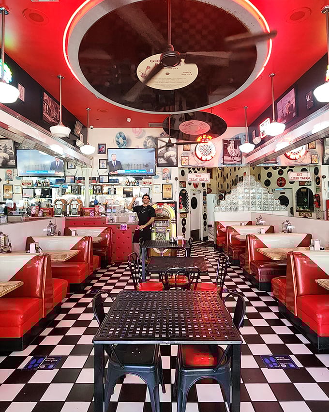 Red vinyl booths, checkered floors, and vinyl records suspended from the ceiling—this isn't decoration, it's a full-sensory portal to simpler times.
