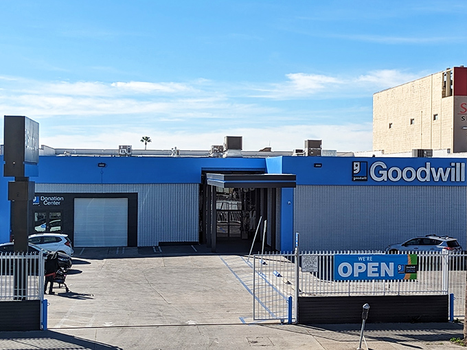 Goodwill's blue storefront stands tall among palm trees—a California thrift paradise where one person's "meh" becomes another's "magnificent!"