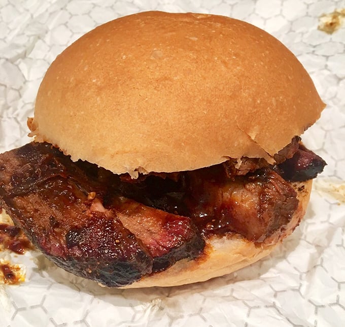 Behold the star attraction: a brisket sandwich sporting that coveted smoke ring. The simple bun knows its role—just transport this smoky treasure to your face.