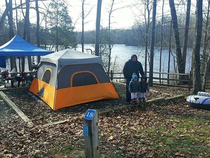 Winter camping with a view: fallen leaves crunch underfoot as this family creates memories at their lakeside campsite, proving nature doesn't close for the season.