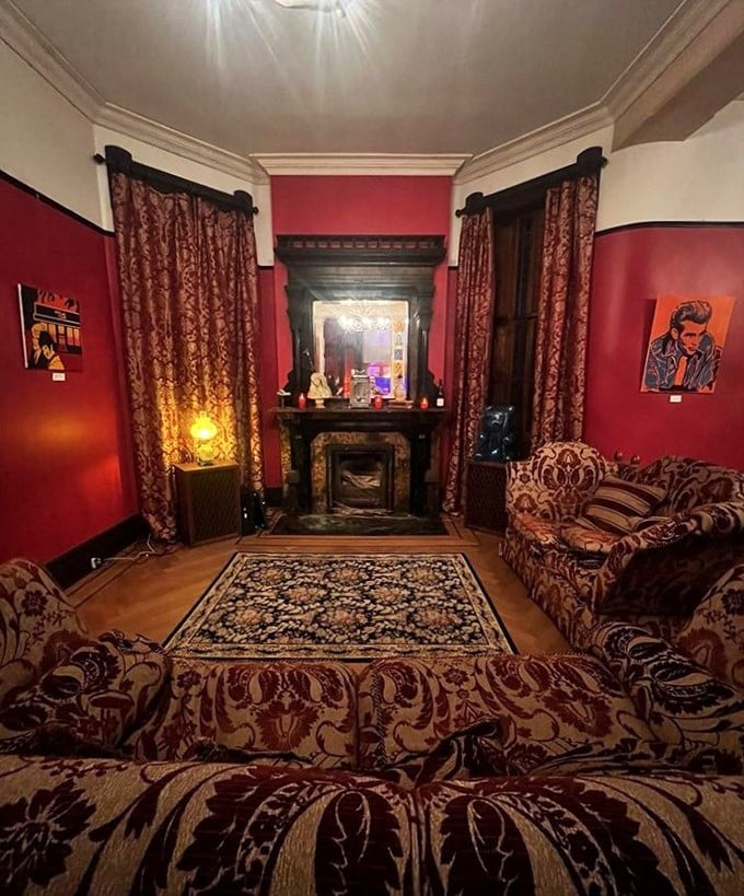 Rich crimson walls embrace vintage furnishings in this parlor where you half-expect to hear phantom piano notes drifting through the air.