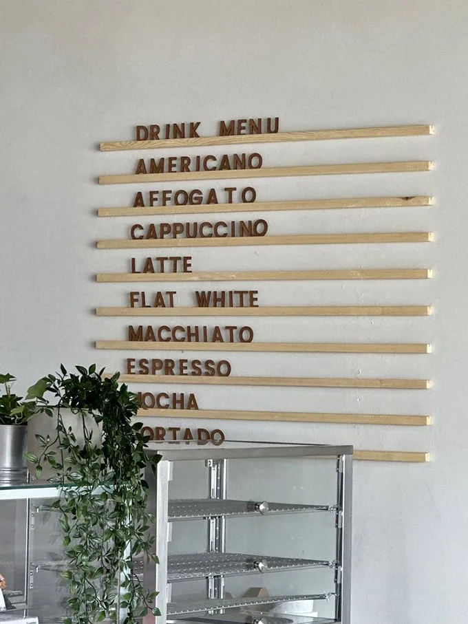 Coffee options lined up like delicious soldiers ready for duty. The wooden menu board is both rustic and sophisticated—just like the beverages it advertises.