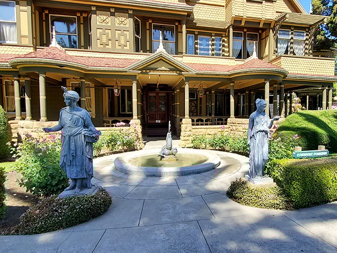 Classical statues stand guard at this serene fountain, offering a moment of symmetry in a house famously designed to confuse.