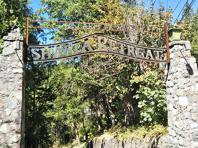 The entrance to Shasta Retreat promises adventure beyond its stone pillars. Nature's cathedral awaits just beyond this rustic gateway.