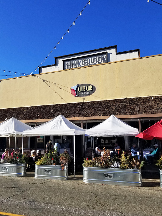 The Club Car Restaurant offers outdoor dining under string lights—where locals gather for comfort food that makes your grandmother's cooking seem merely adequate.