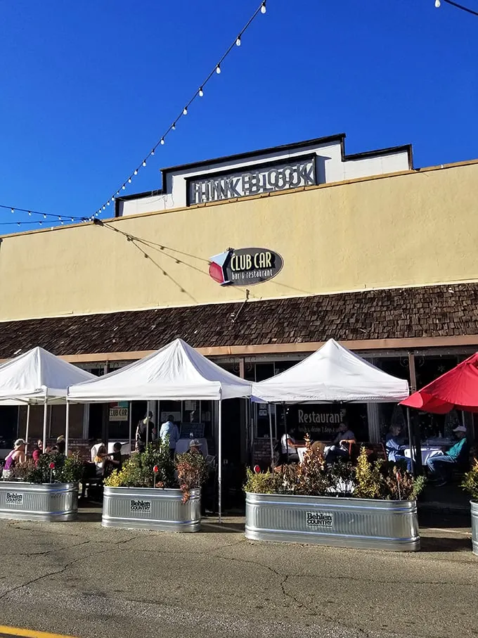The Club Car Restaurant offers outdoor dining under string lights—where locals gather for comfort food that makes your grandmother's cooking seem merely adequate.