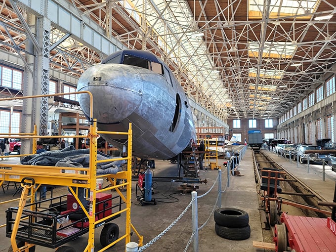 This gleaming silver DC-3 aircraft stands majestically in the Back Shop, a testament to aviation history that seems ready to soar despite its indoor confinement.