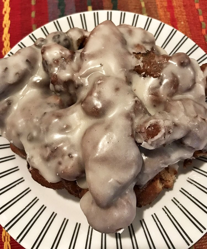 Behold the apple fritter that launched a thousand road trips – gloriously glazed chaos on a plate.