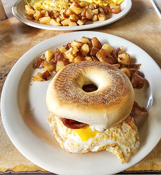 Breakfast architecture at its finest—a perfectly toasted bagel sandwich with home fries so crispy they deserve their own fan club.