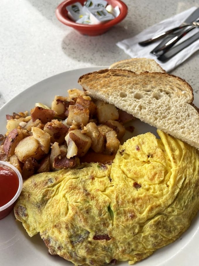 This isn't just an omelet—it's breakfast architecture. Golden eggs folded over savory fillings with those legendary home fries that could convert a potato skeptic.