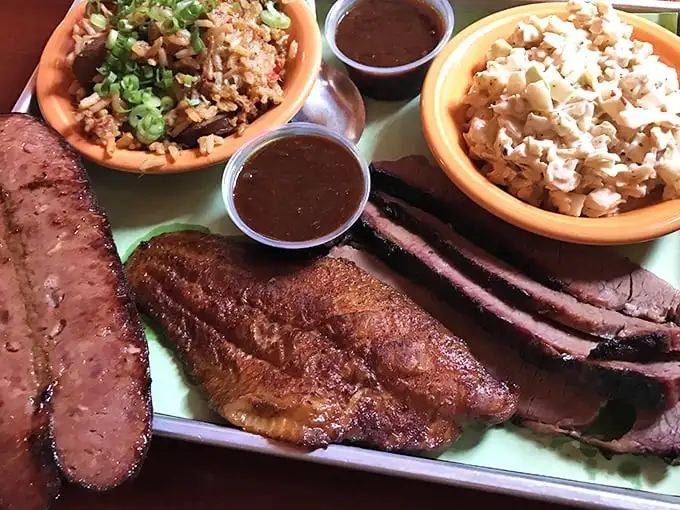 Meat paradise found! The holy trinity of barbecue—sausage, fish, and brisket—flanked by sides that refuse to be mere afterthoughts.