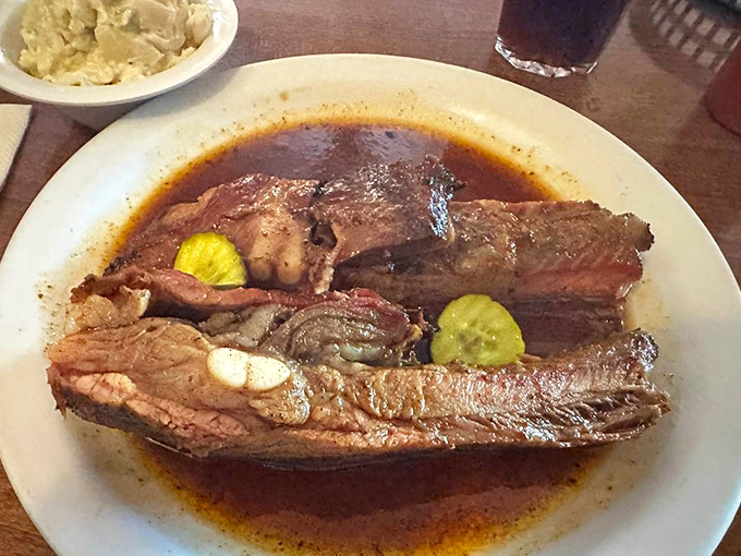 These spare ribs aren't just falling off the bone—they're practically jumping into your mouth. Note the pickle garnish adding that perfect tang.