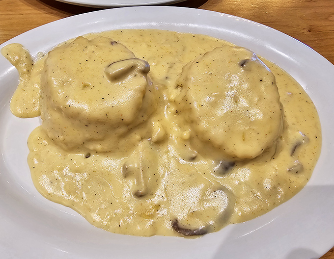 Behold the holy grail of comfort food – fluffy biscuits drowning in creamy, peppery gravy perfection.