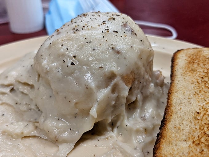Behold the star attraction: a fluffy buttermilk biscuit swimming in peppery sausage gravy. This isn't just breakfast—it's edible poetry that's worth crossing state lines for.