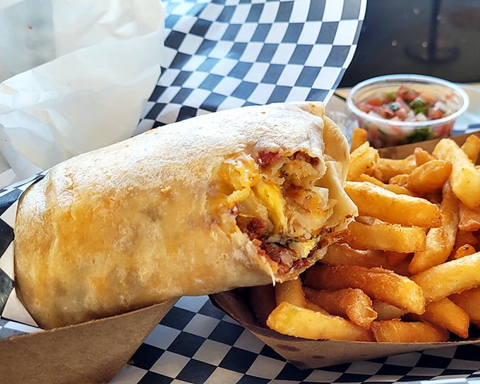 Behold the breakfast burrito in its natural habitat—perfectly grilled, stuffed with morning magic, and flanked by golden fries that demand attention.